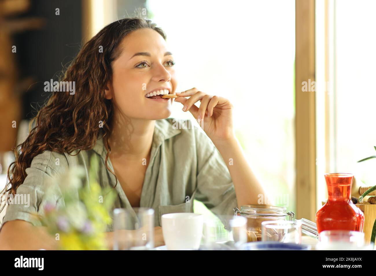 Happy woman eating cookie sitting in a restaurant Stock Photo - Alamy
