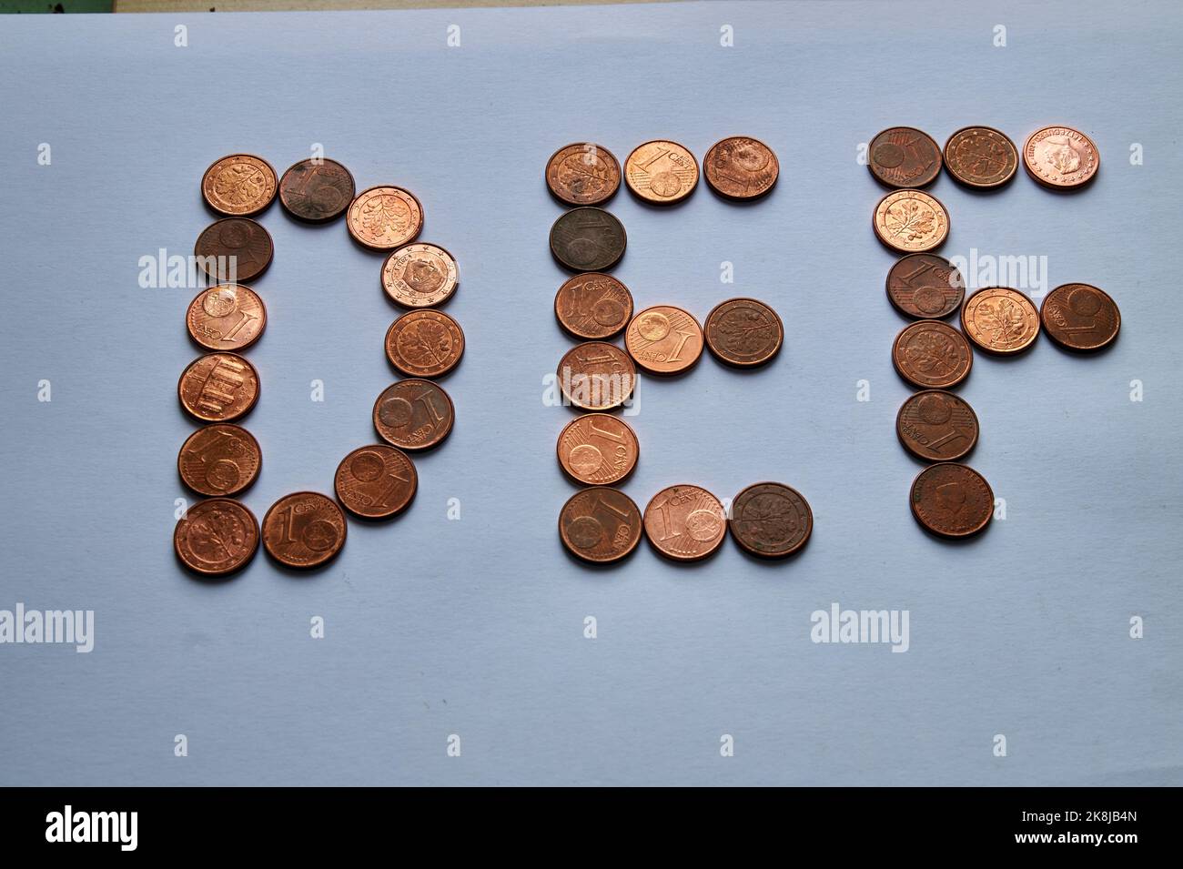 Letters d e f of copper coins insulated on a white sheet of paper Stock ...