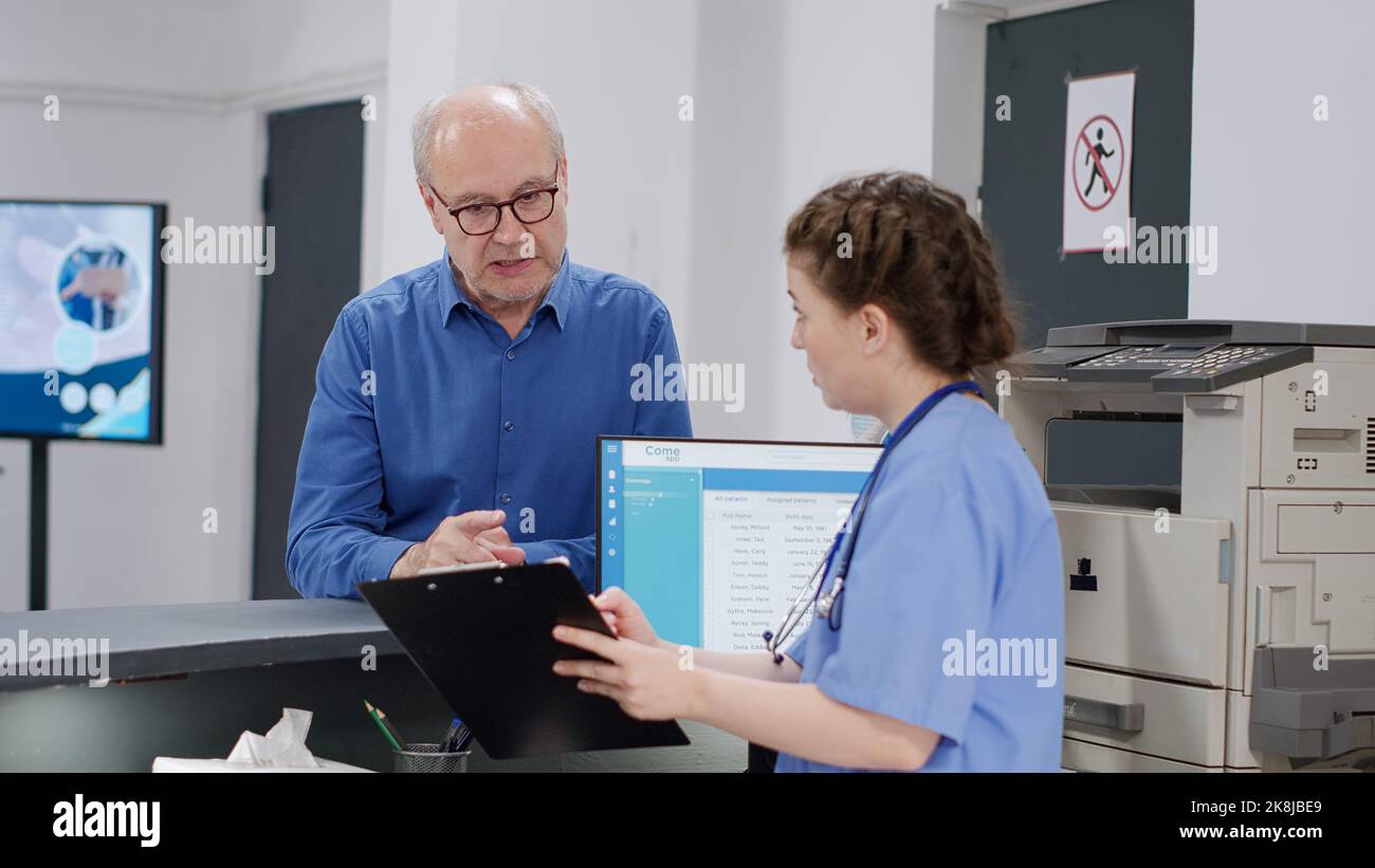 Medical assistant and old patient filling in checkup report papers at ...
