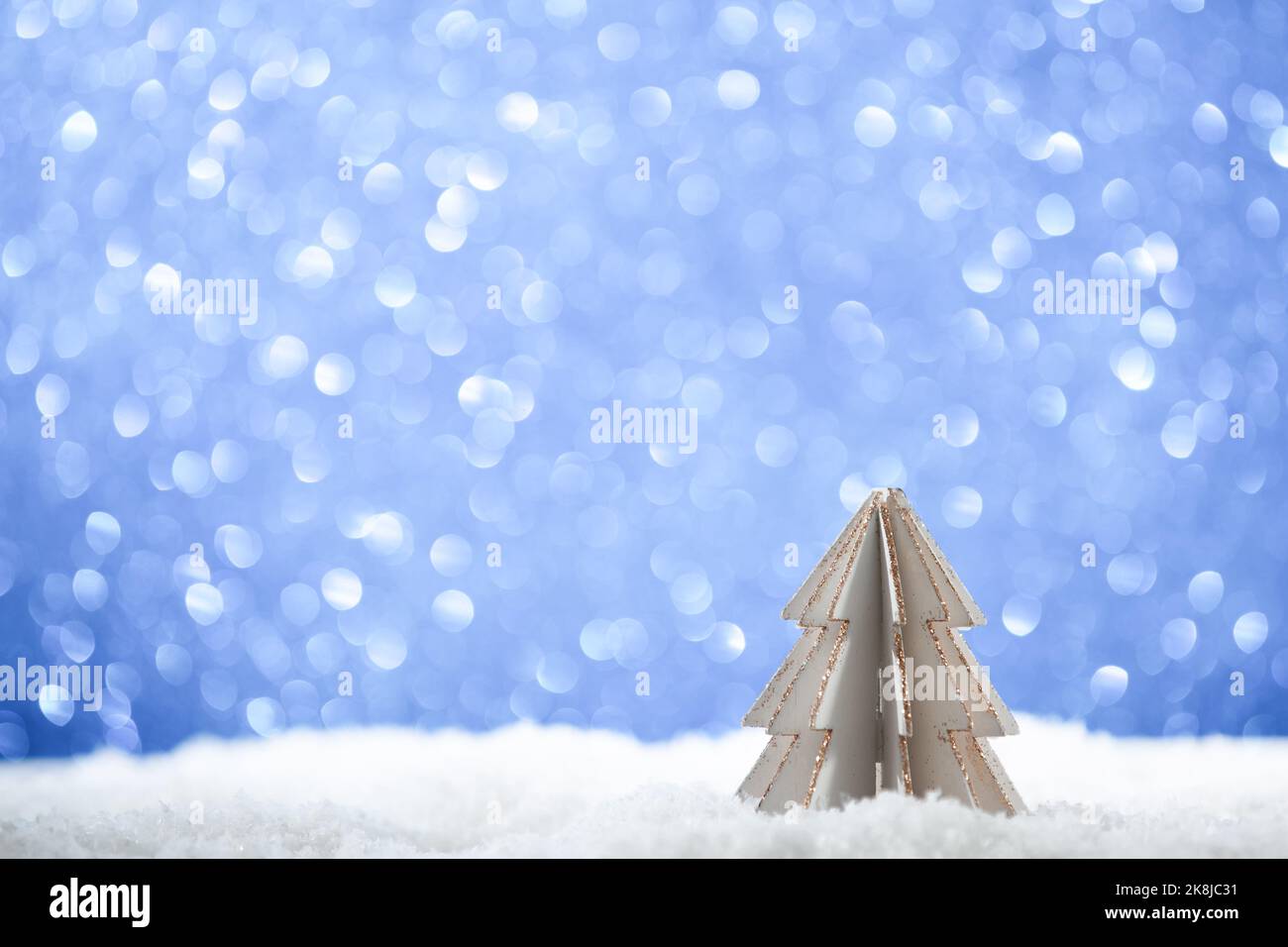 Small wooden Christmas tree on snow and blue bokeh background.Postcard ...