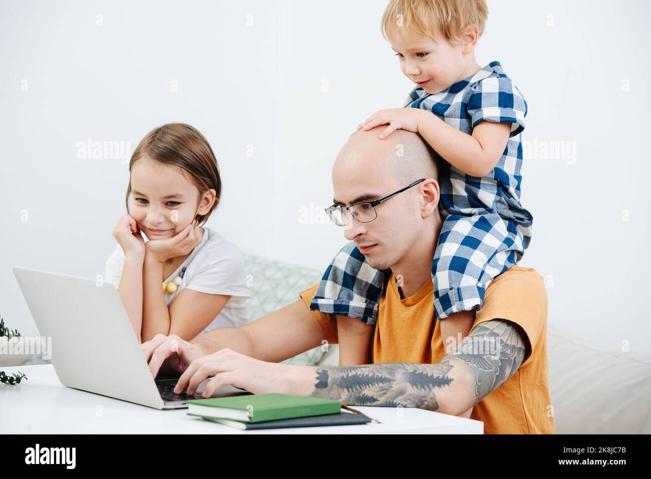 Cheeky bored kids messing with their father working on his laptop. Boy ...