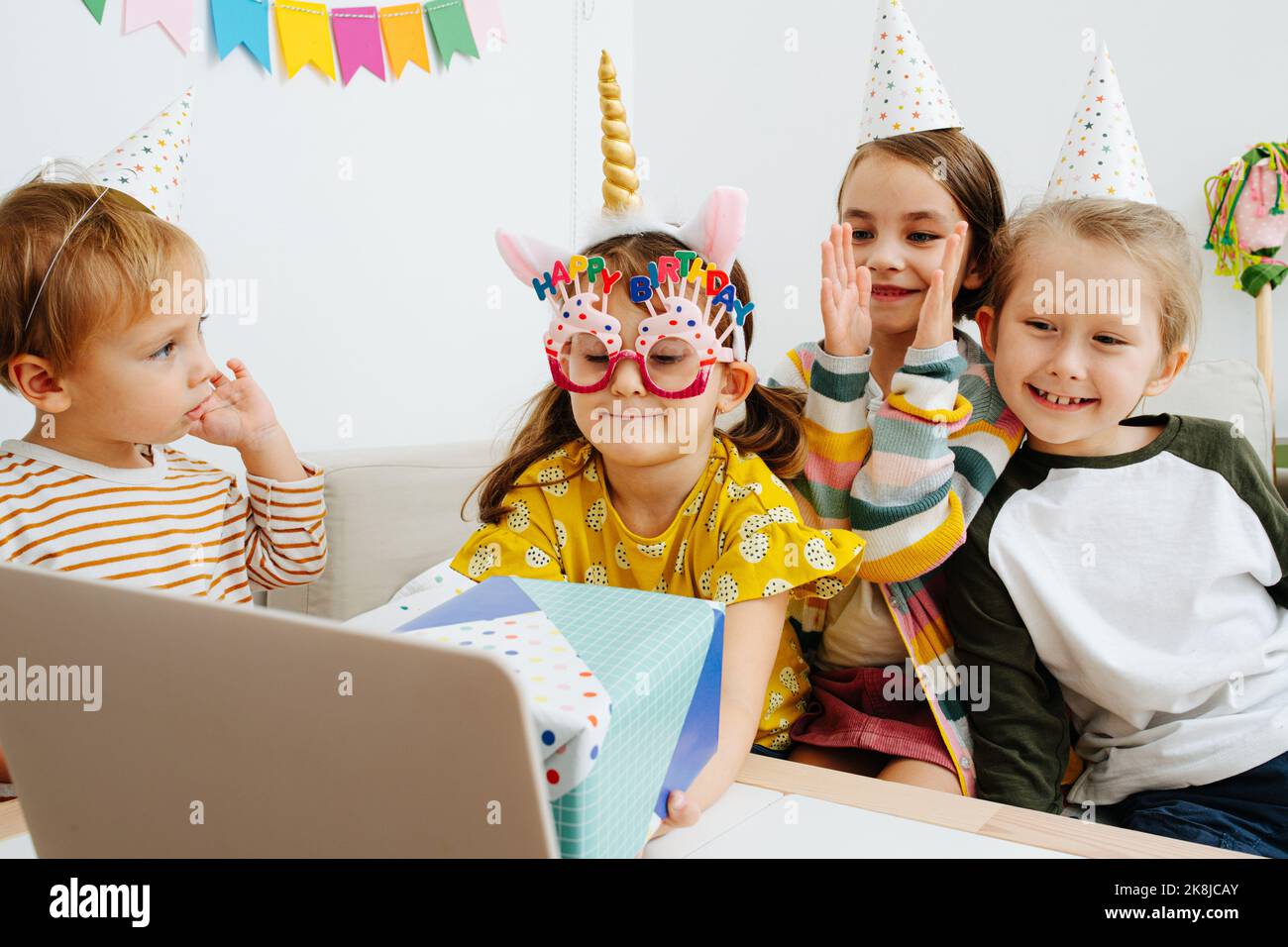 Chatting on video call little kids in party hats gathered around a ...