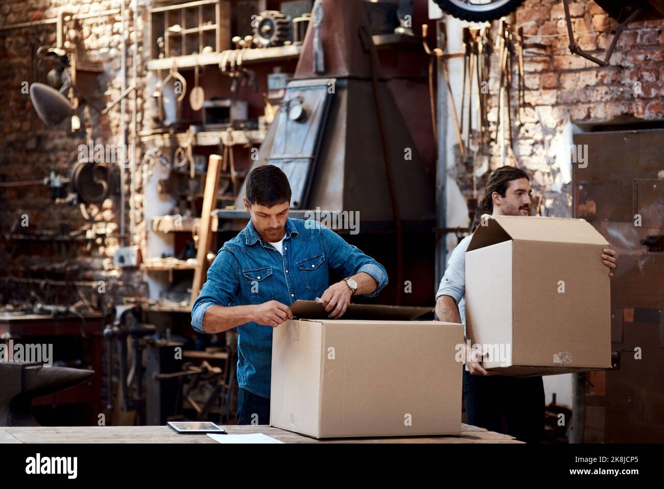 Things get easier when we work together. two young businessmen carrying ...