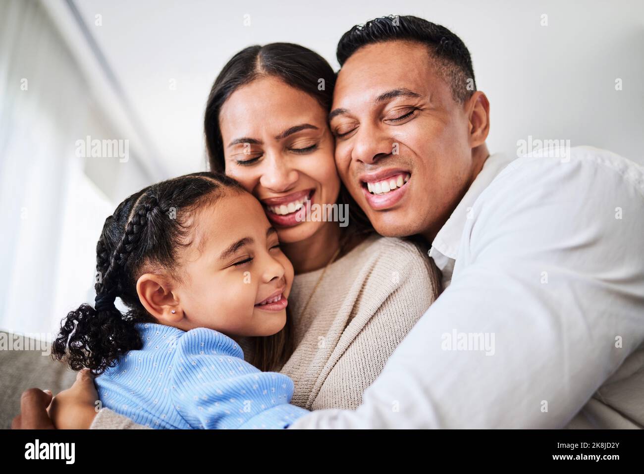 Family hug, happy love and parents with smile for child on sofa in home ...