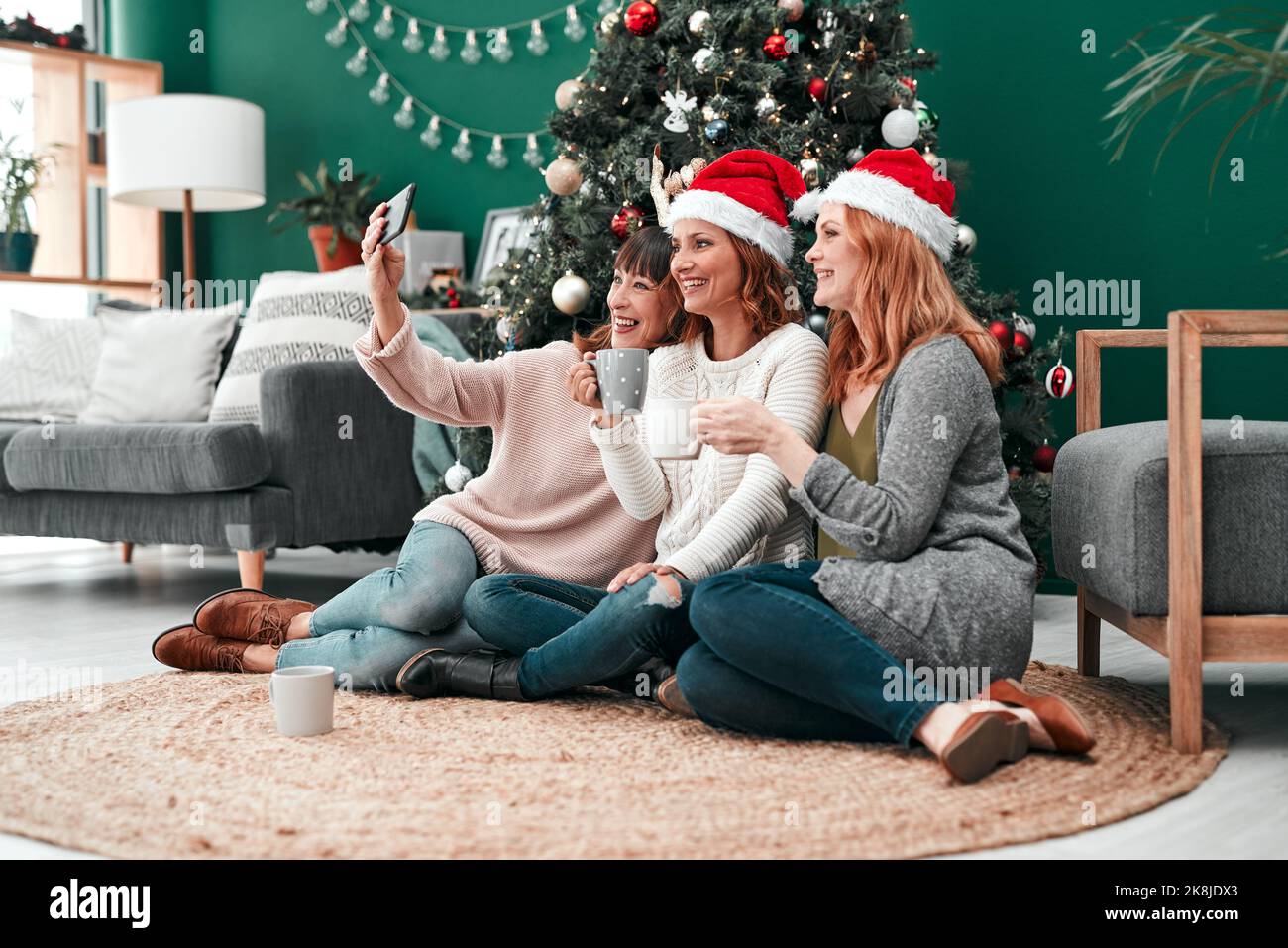 Captured smiles. three attractive women taking Christmas selfies ...