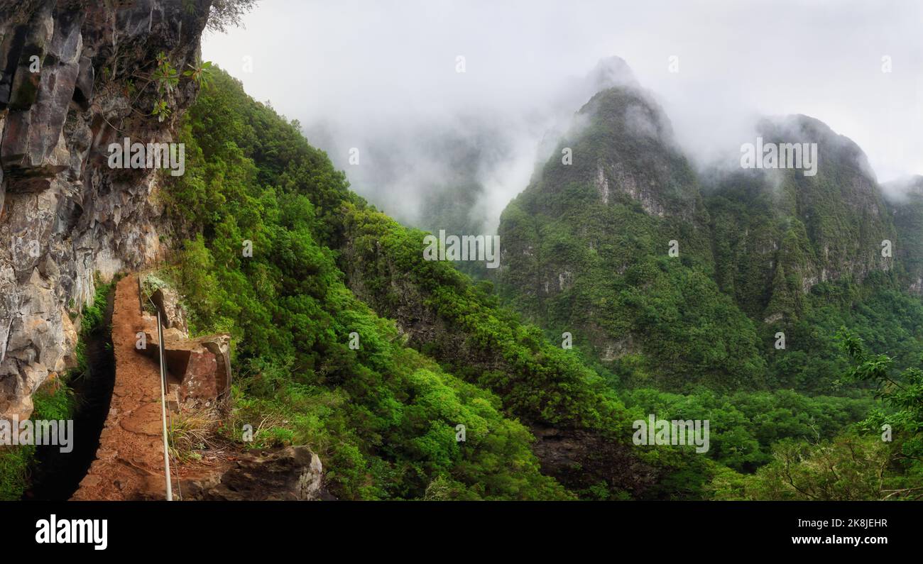Hikers walking on a narrow path on the edge of the rock during Levada ...