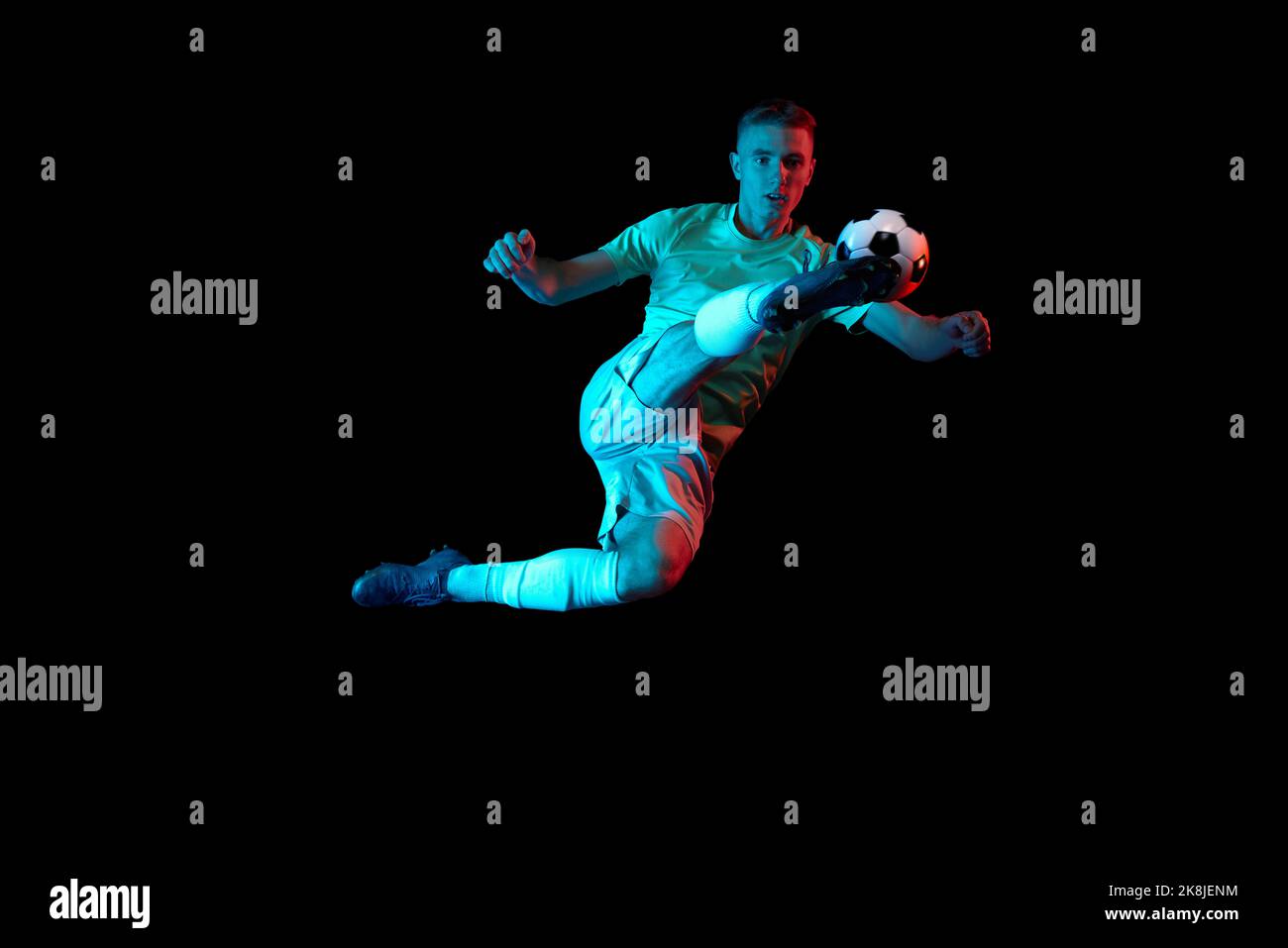 Dynamic shot of young active football player in action isolated on dark ...