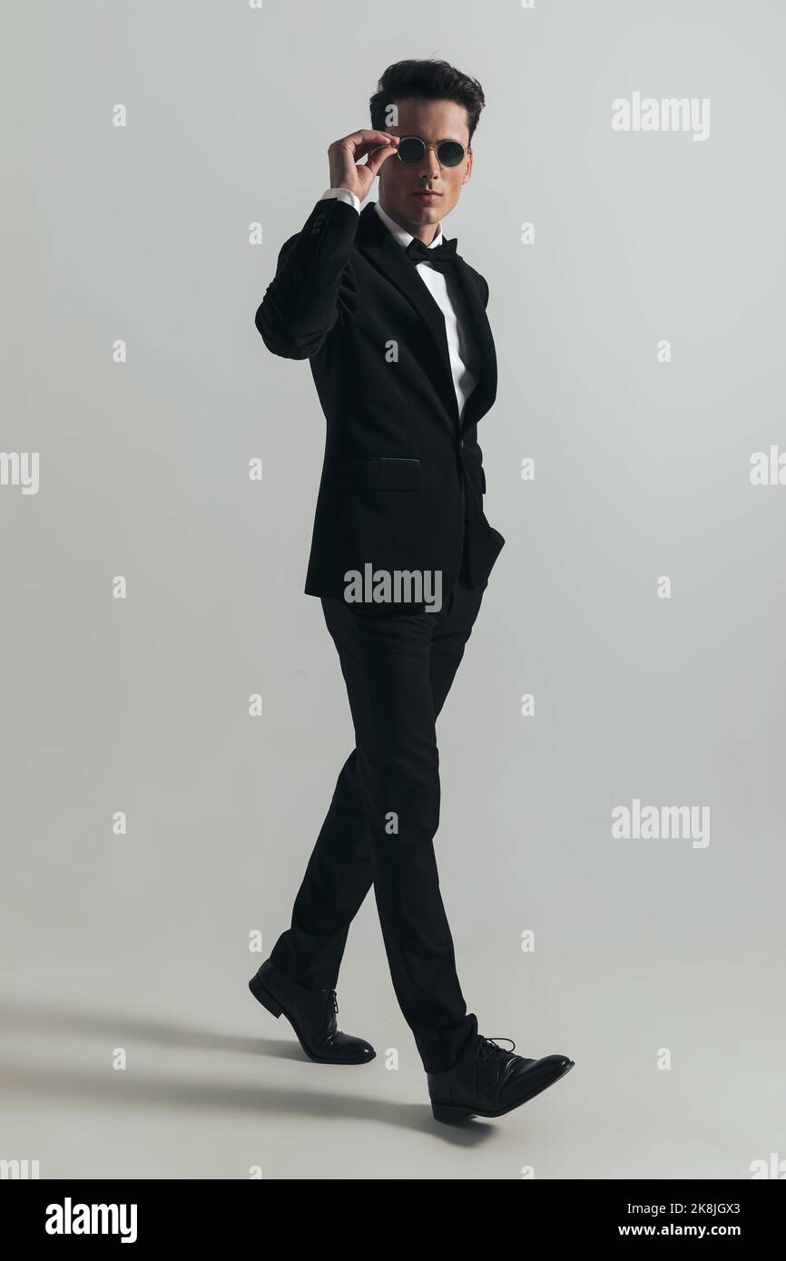 full body picture of stylish young groom wearing black tuxedo and ...