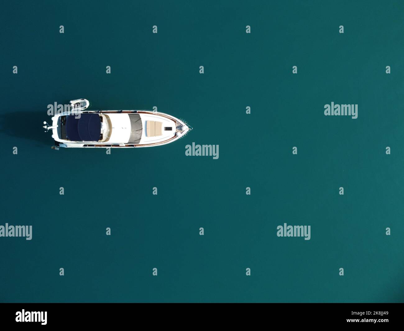 Aerial yacht on calm sea. Luxury cruise trip. View from above of white boat on deep blue water ...