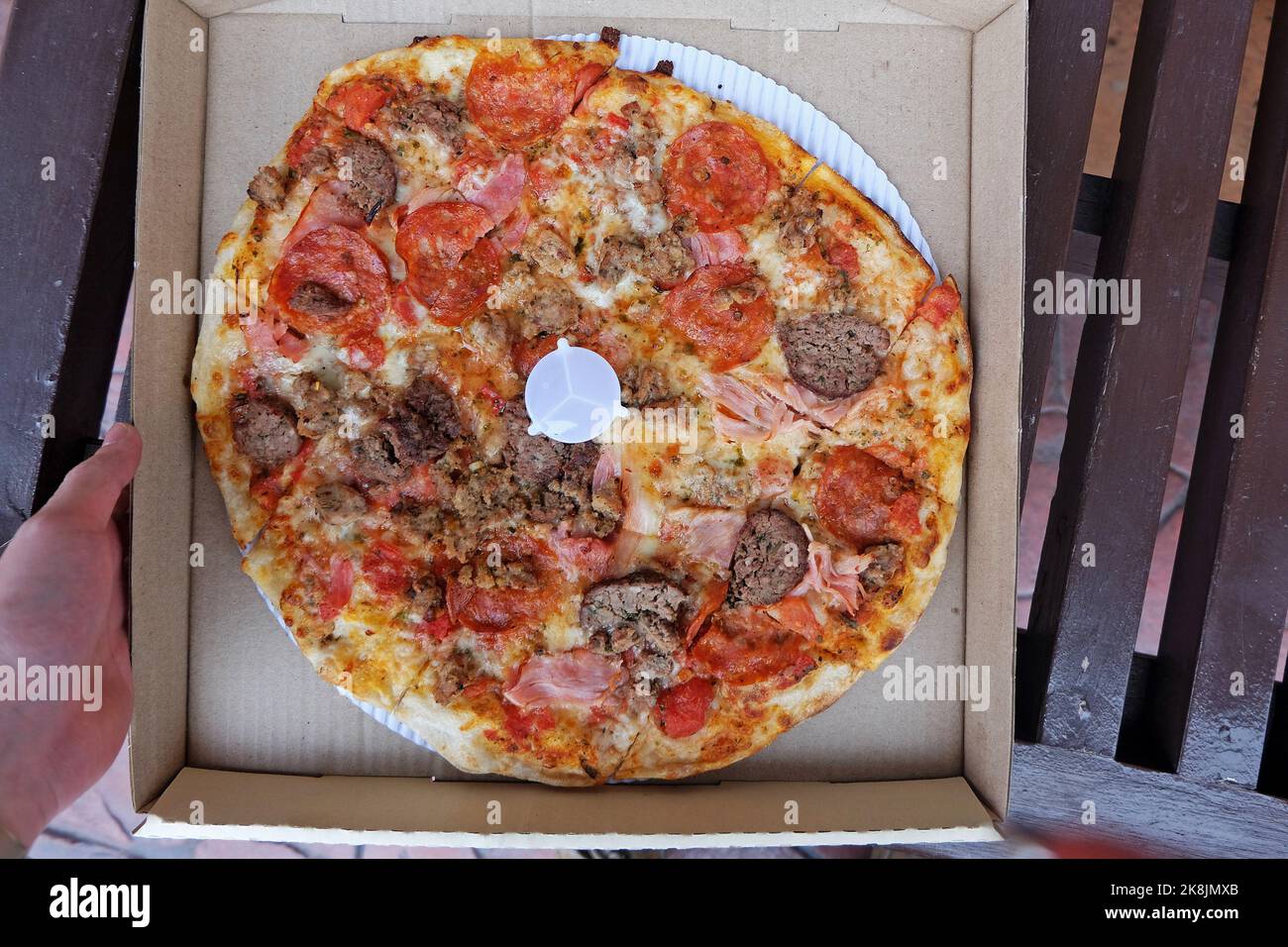 Close up box of Thin crust pizza topped with ham pepperoni and sausages ...