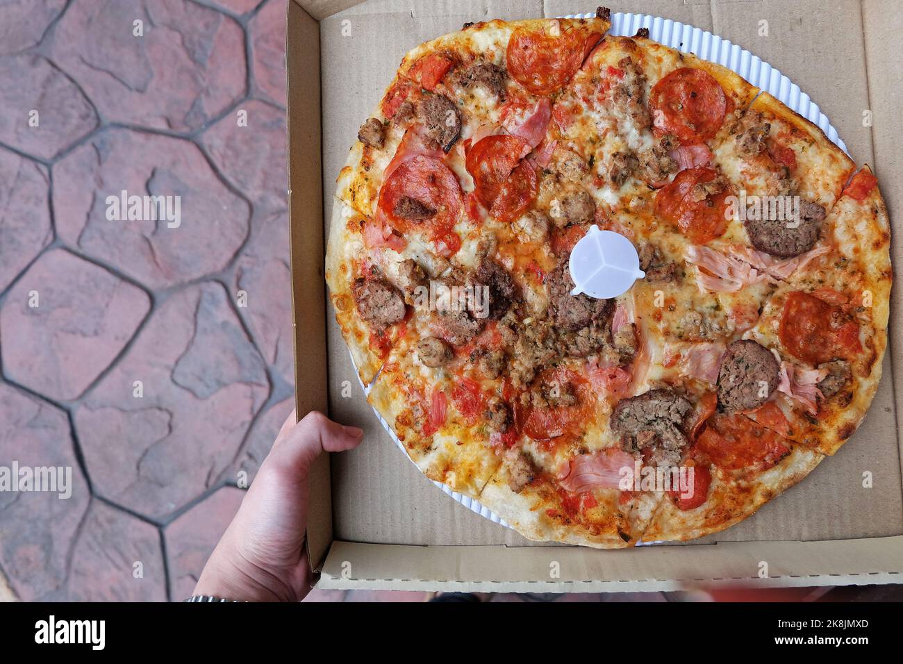 Close up box of Thin crust pizza topped with ham pepperoni and sausages ...