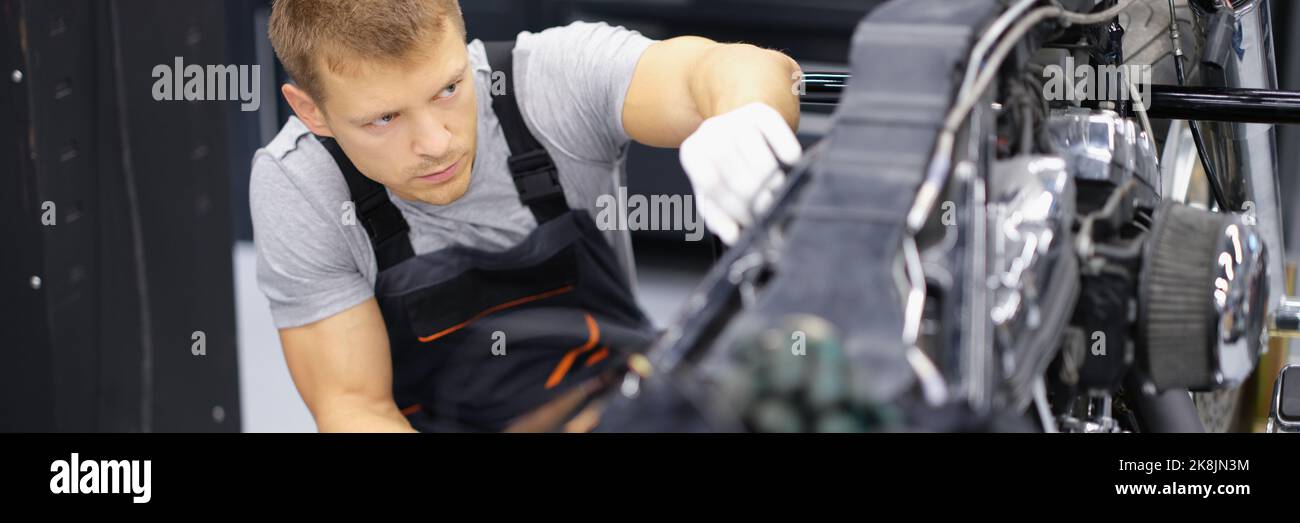 Concentrated serious handyman with tool fix damaged motorbike in garage ...