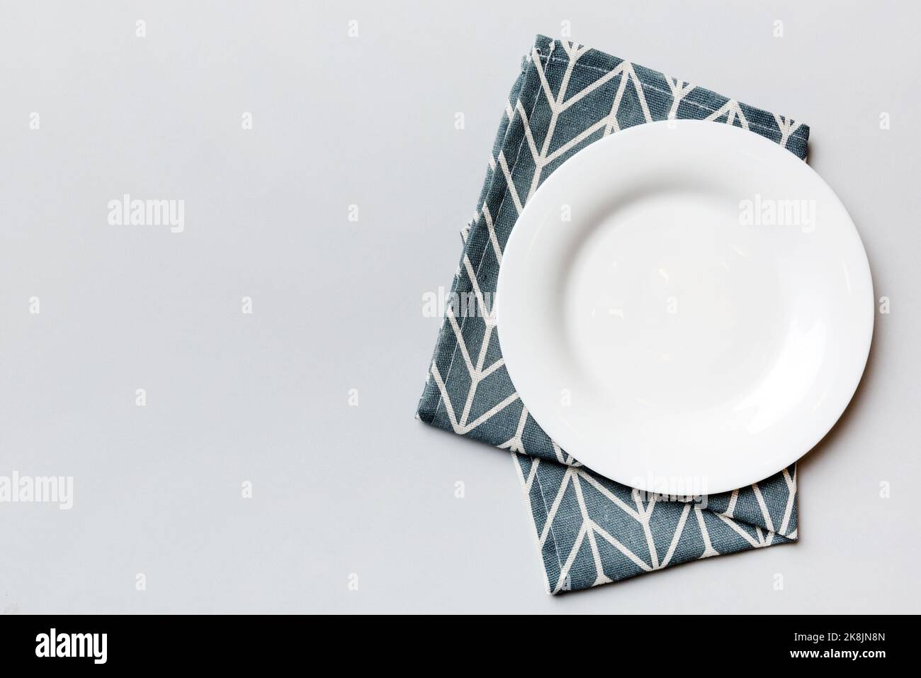 Top view on colored background empty round white plate on tablecloth ...