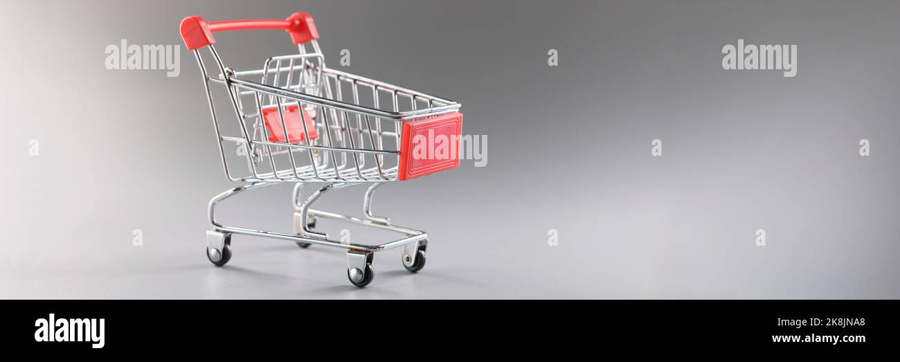 Empty shopping cart against grey background, single miniature model of ...