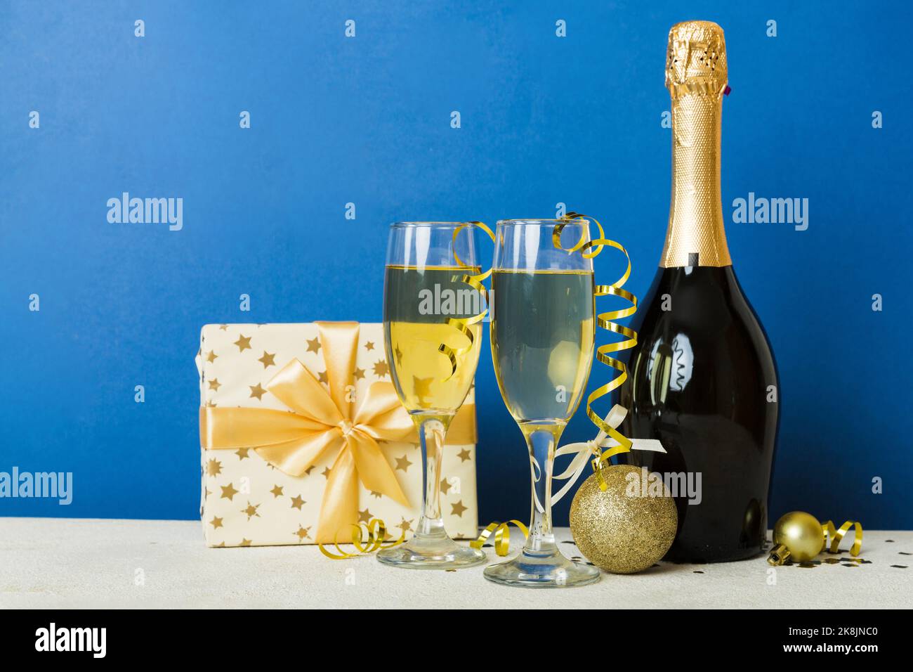 Champagne bottle with confetti, glasses and christmas decor on colored ...