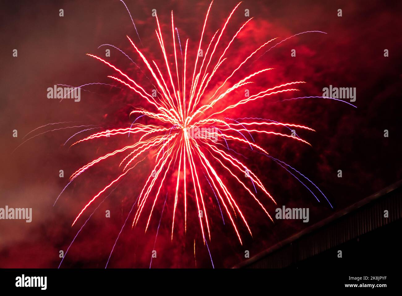 Beautiful red and blue fireworks glowing against a smoky night sky ...