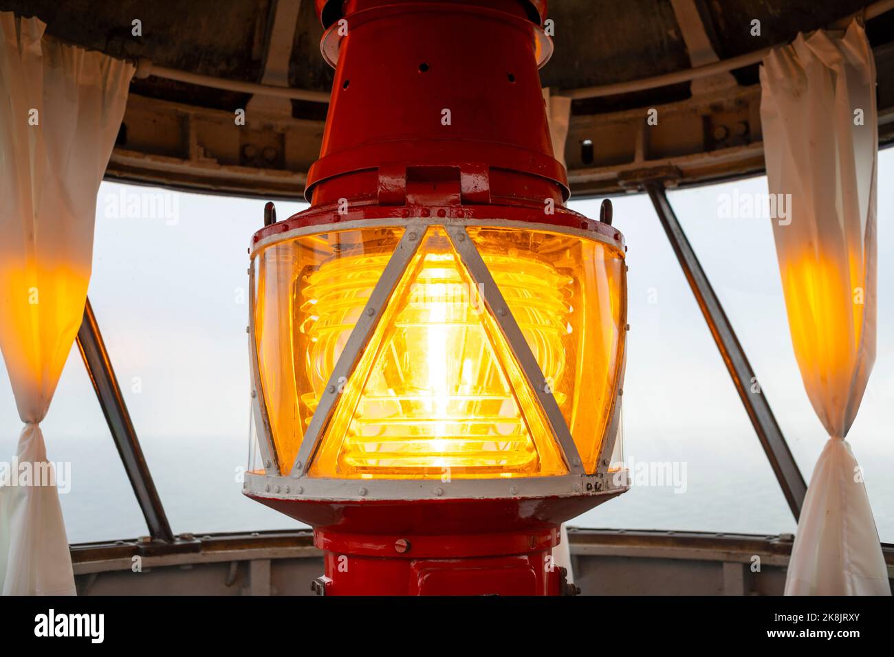 Close up of a lighthouse lamp from inside looking out windows to lake ...
