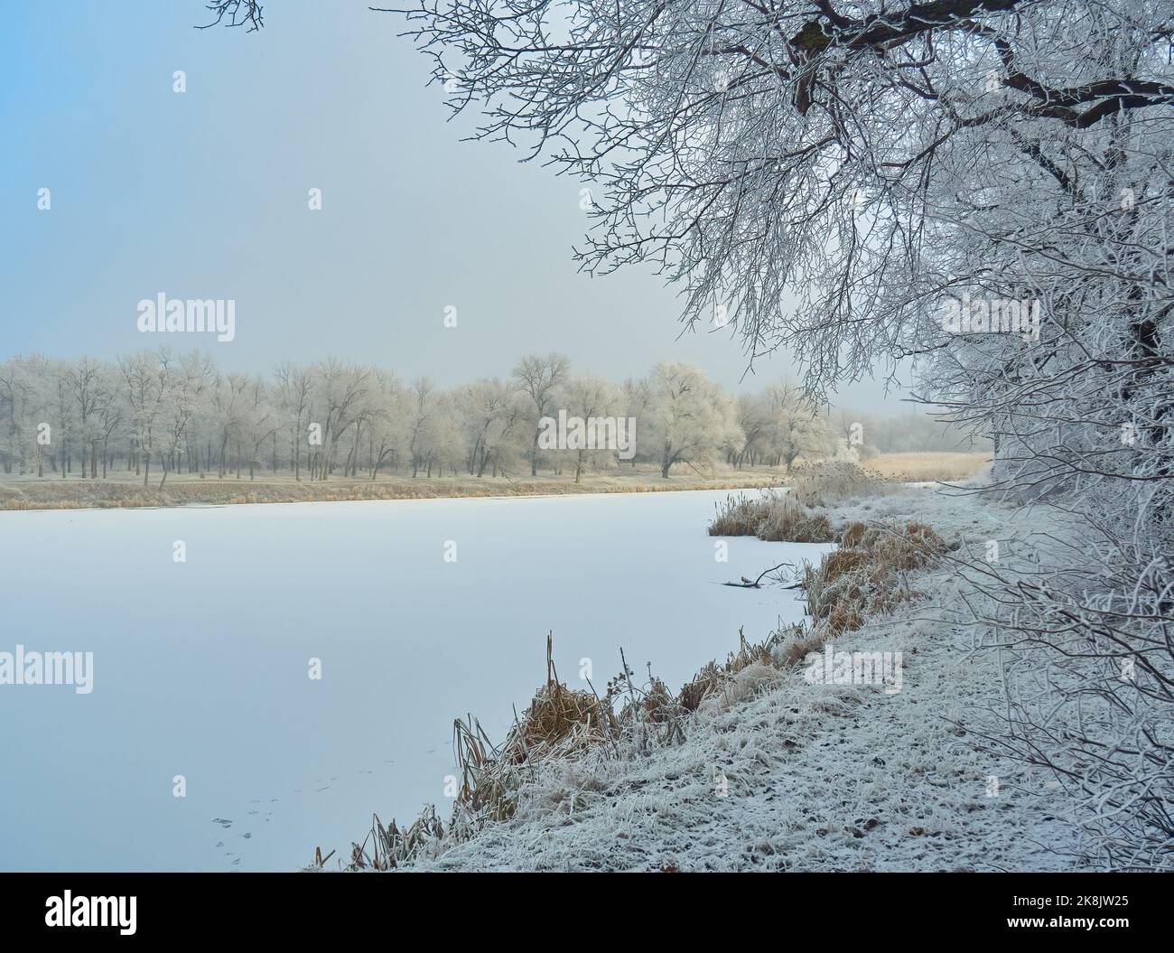 frozen lake on sunny winter's day with blue sky, snow falling Stock ...