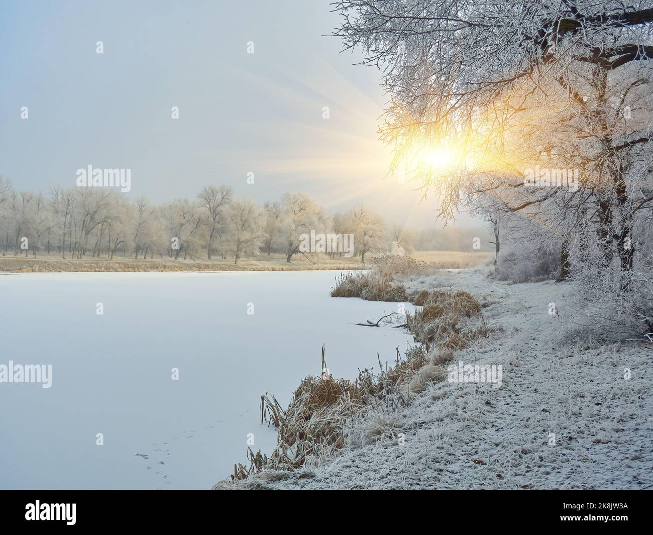 frozen lake on sunny winter's day with blue sky, snow falling Stock ...