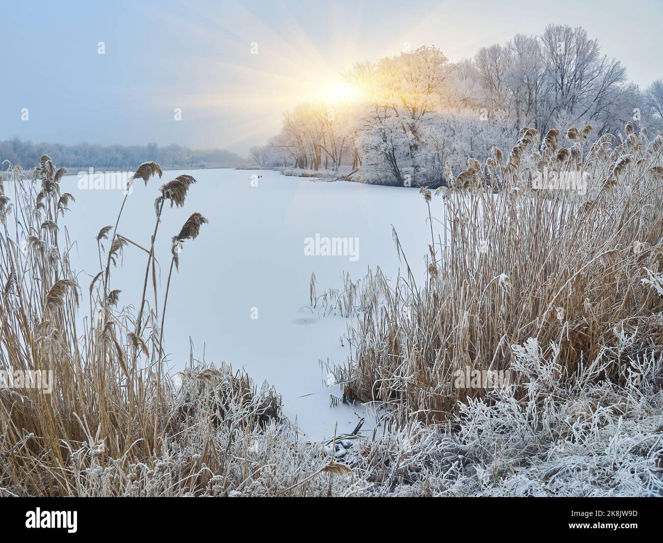 frozen lake on sunny winter's day with blue sky, snow falling Stock ...