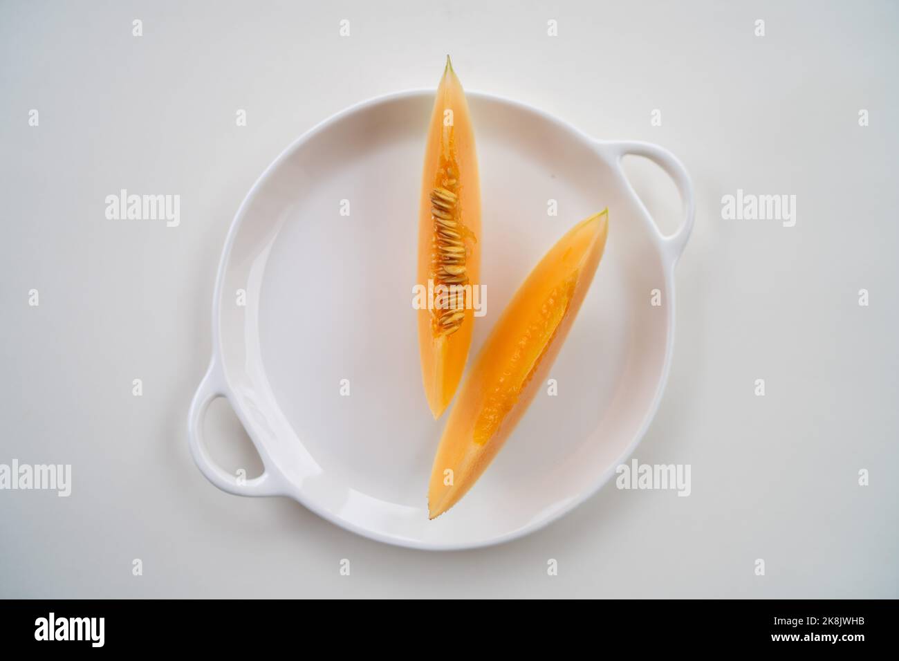 A top view of sweet fresh melon slices on a plate isolated on a white ...