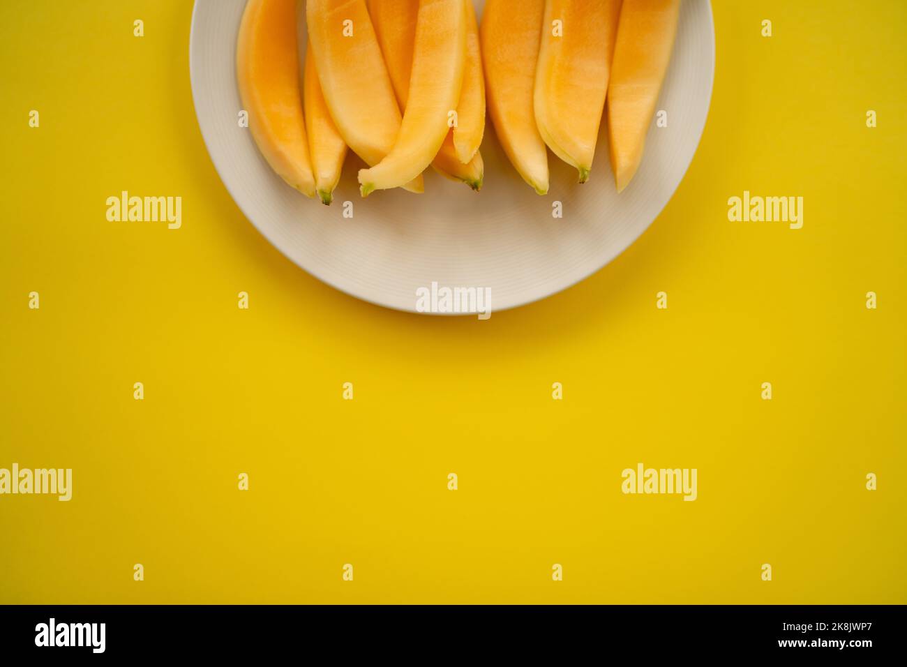 A top view of melon rinds on a plate isolated on a yellow background ...