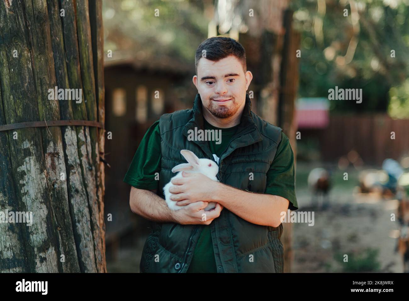 Caretaker with down syndrome taking care of animals in zoo, stroking ...