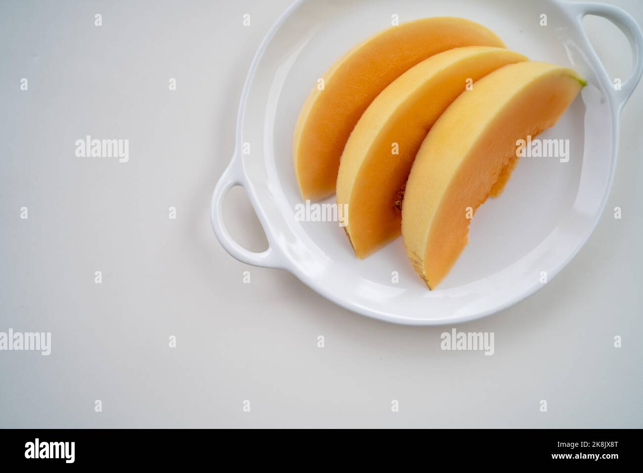 A top view of sweet fresh melon slices on a plate isolated on a white background Stock Photo - Alamy