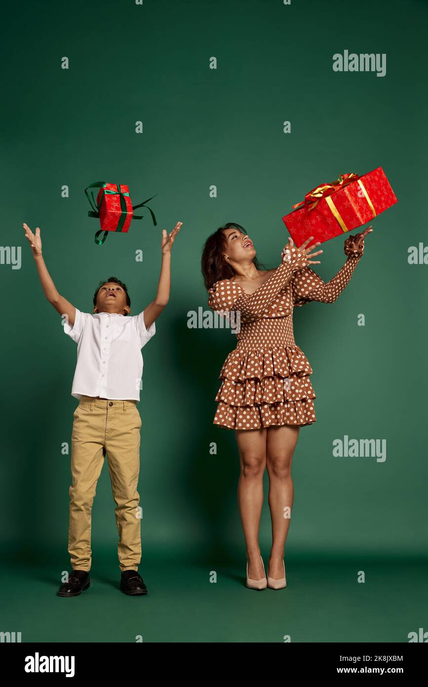Portrait of beautiful woman and teen boy throwing gift boxes isolated ...