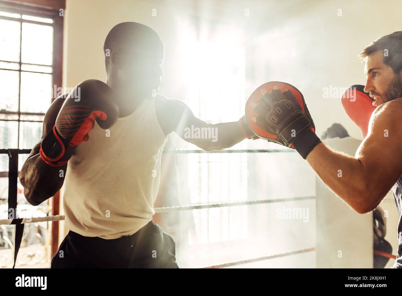 Young black boxer throwing punches on the focus pads held by his ...