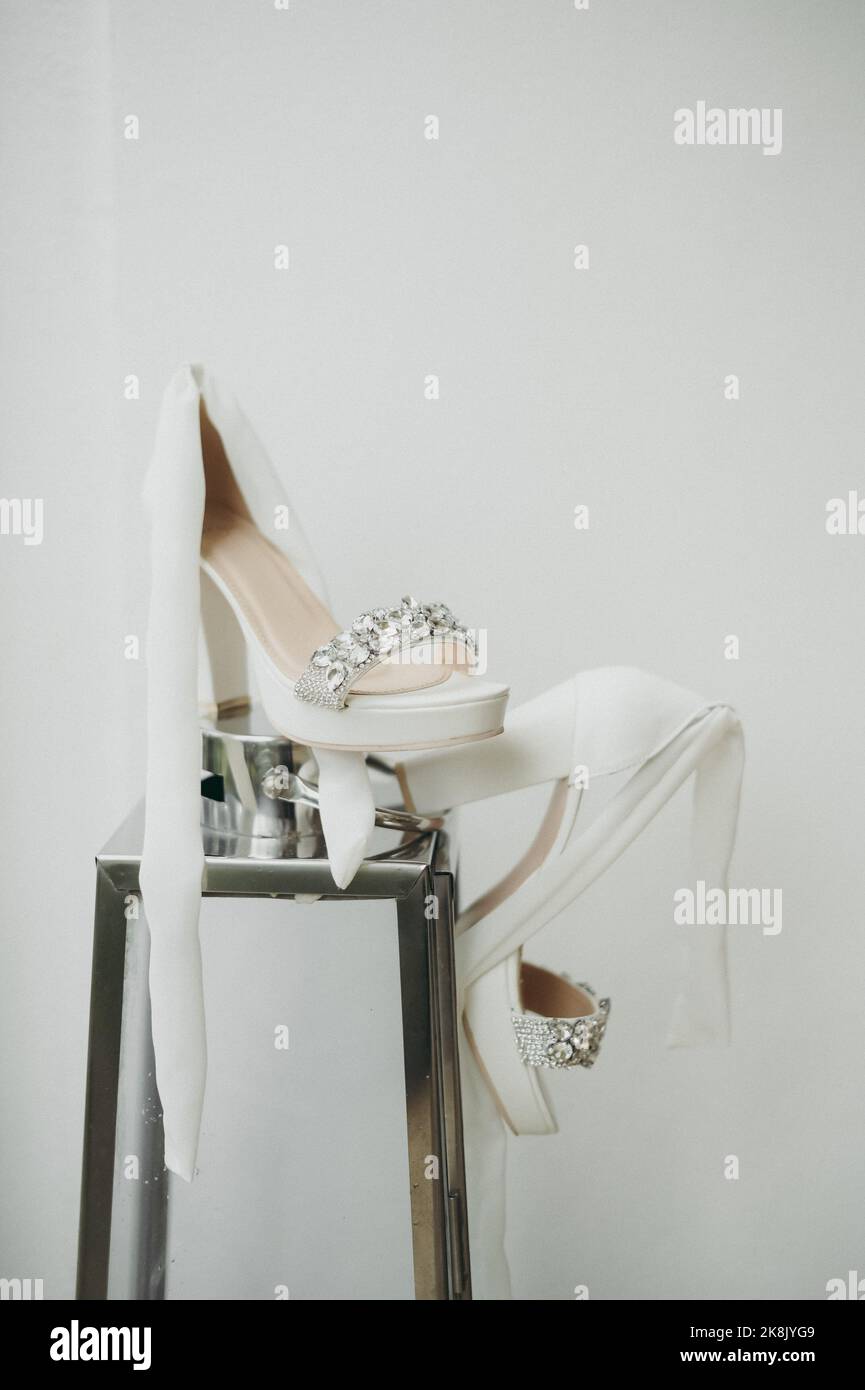 A vertical shot of bridal shoes on a metallic surface on a white ...