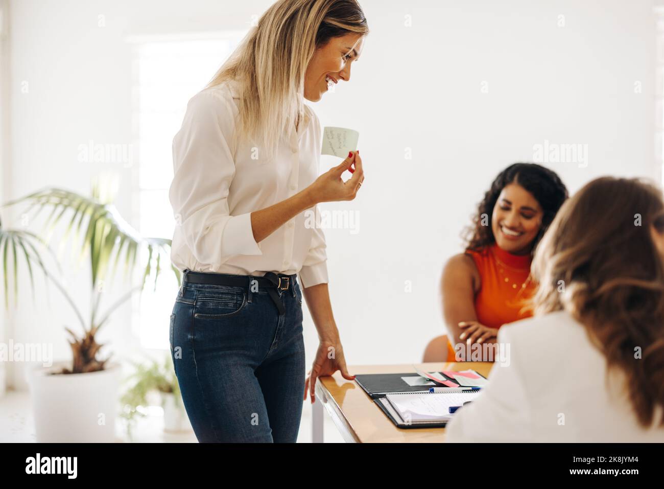 Happy young businesswoman sharing her ideas using sticky notes ...