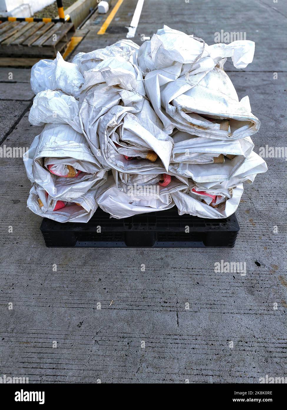 A pile of white paper bags tied and placed on a black wooden pallet ...