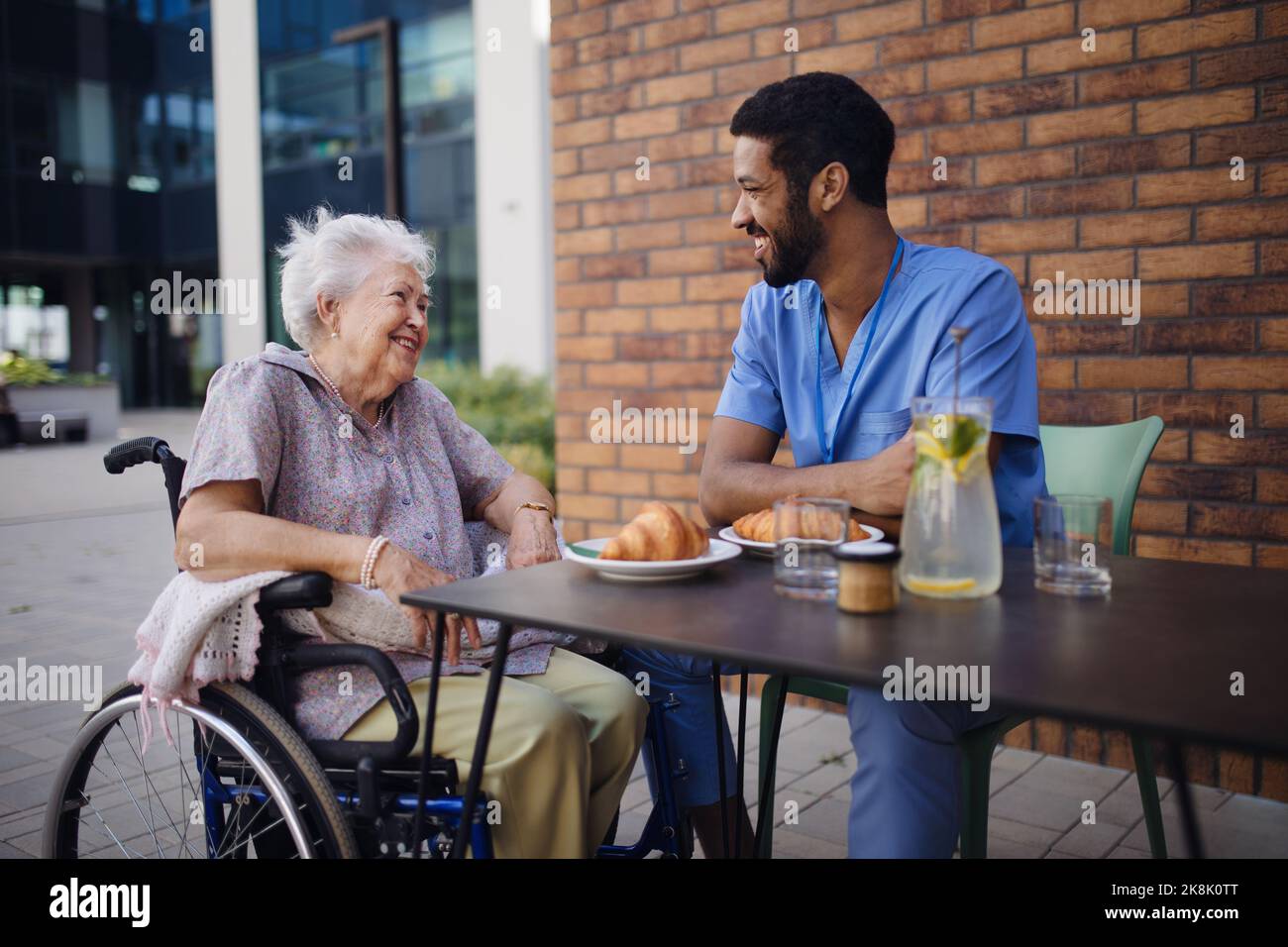 Caregiver having breakfast with his client at cafe Stock Photo - Alamy