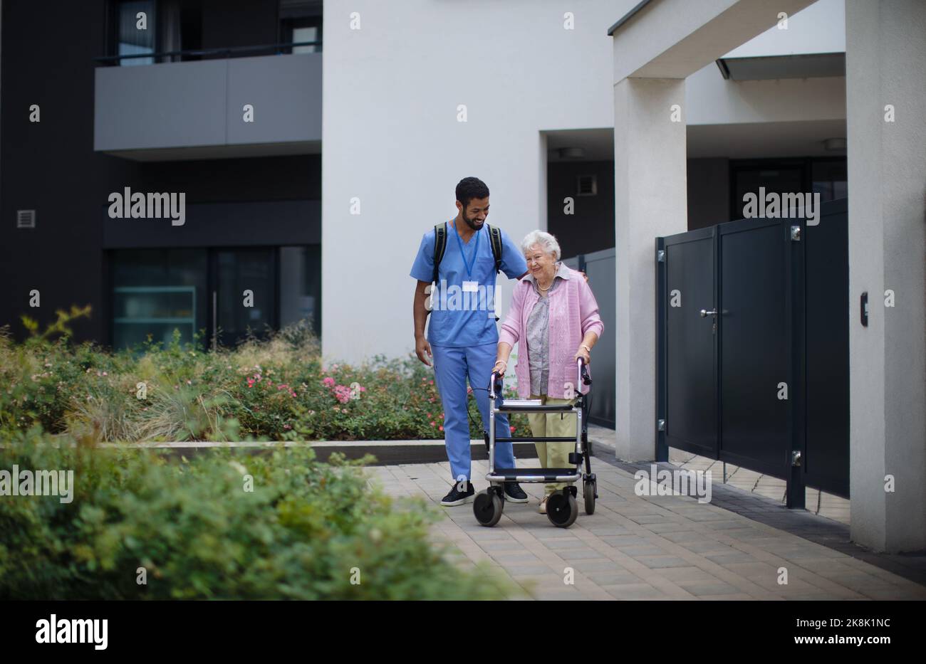 Caregiver walking with senior woman client in front of nurishing home ...
