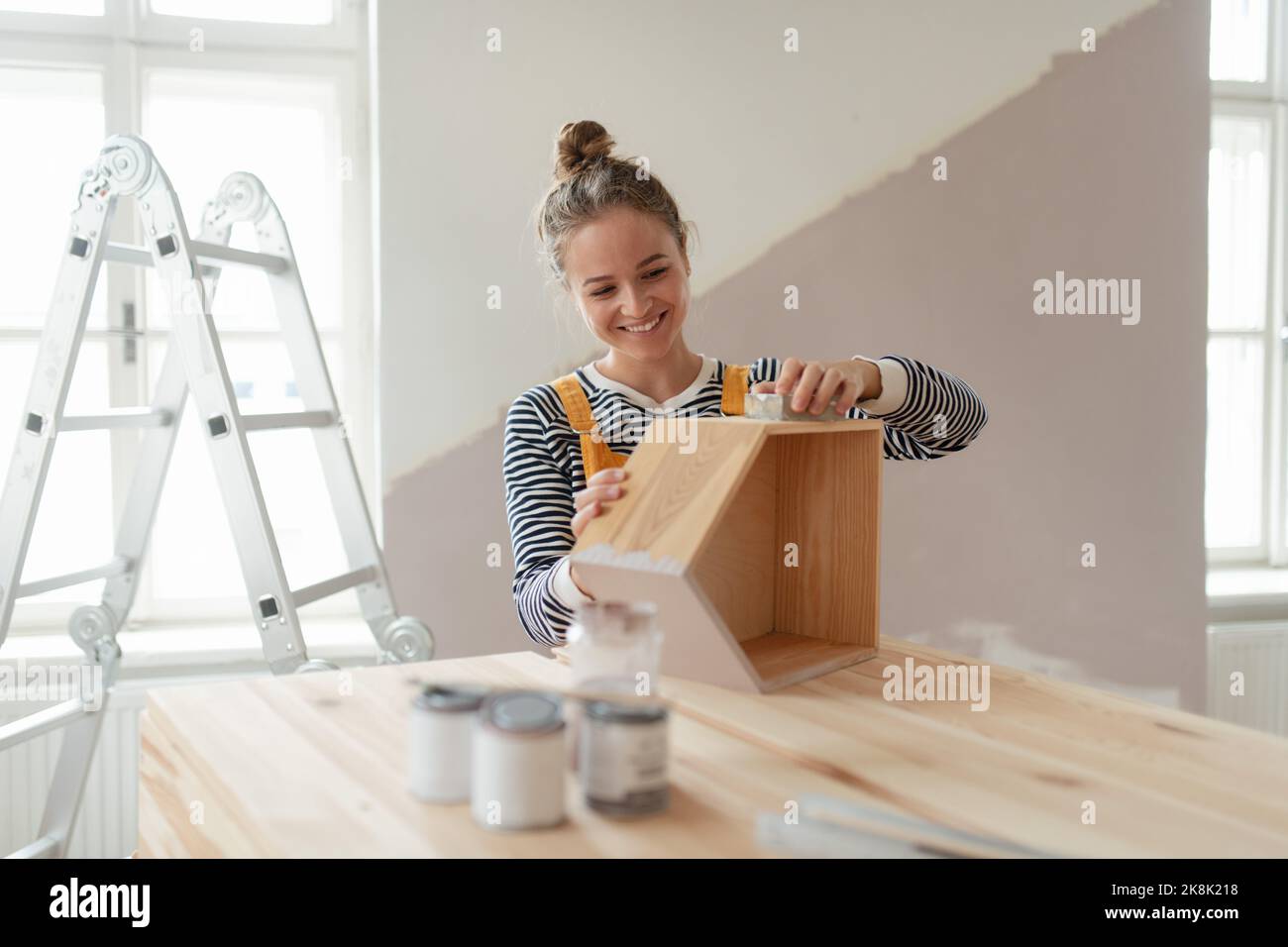 Portrait of young woman remaking shelf in her new flat. Concept of ...
