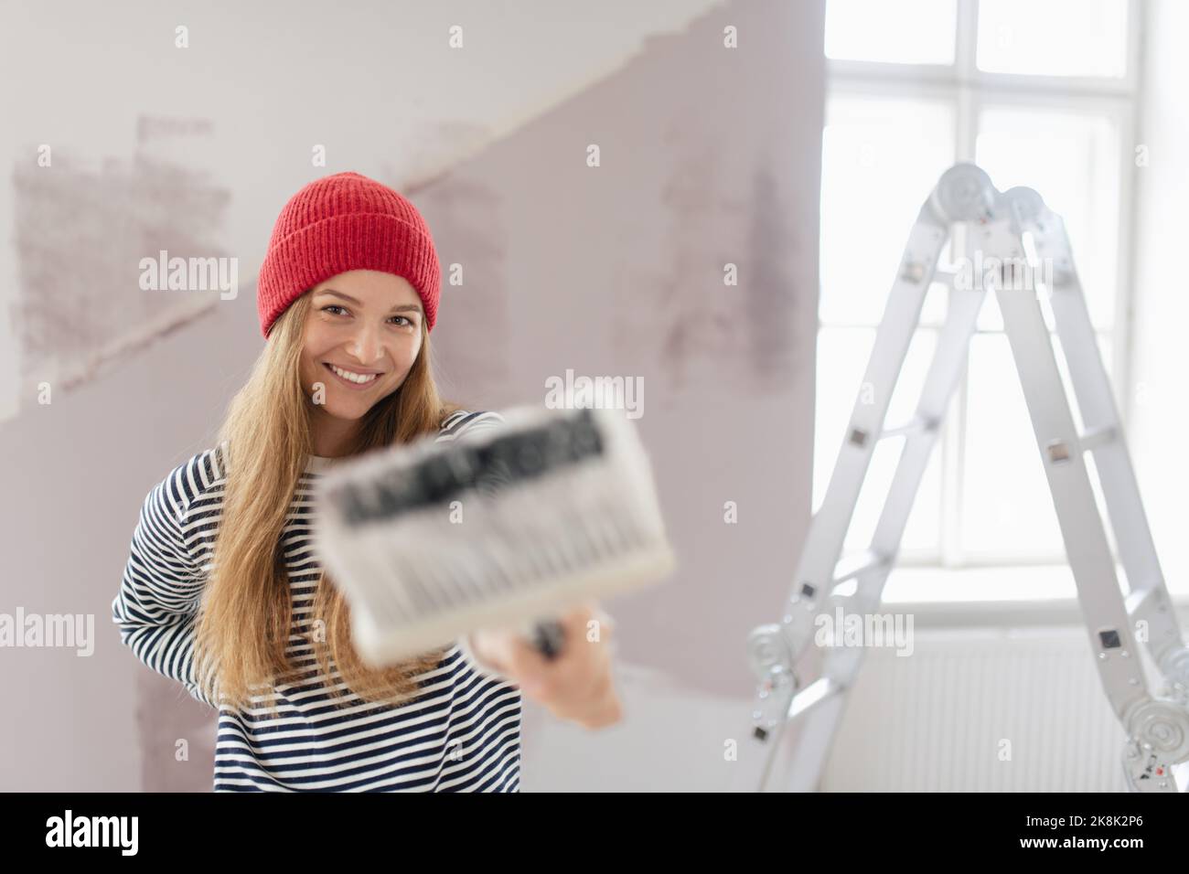 Happy young woman remaking her new flat, painting walls. Concept of ...
