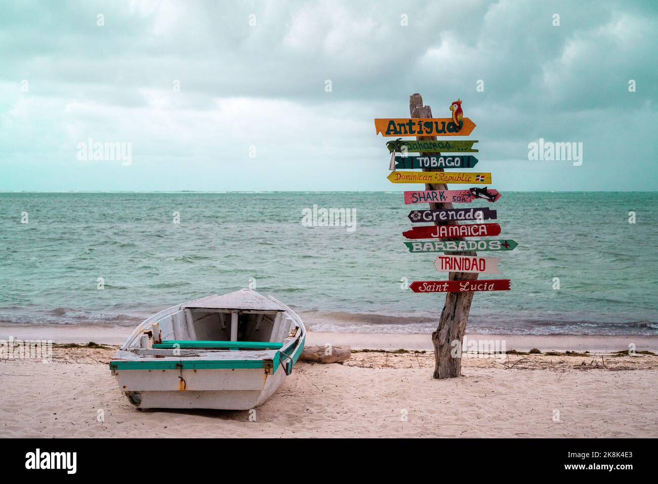 A boat on a sandy beach with directions signs on a trunk and the ...