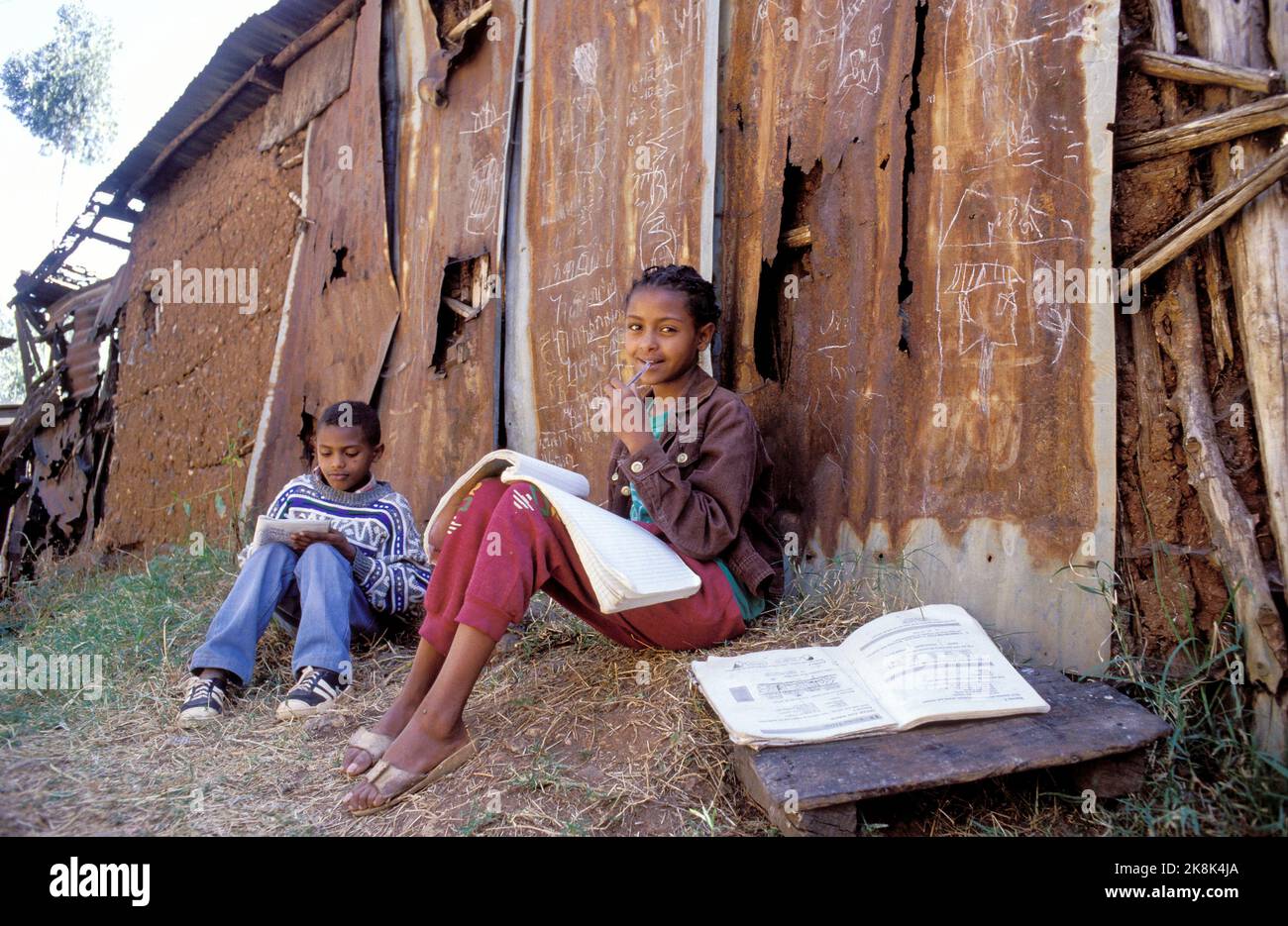 Ethiopia, Tigray; Girl and boy are making homework outside their home ...