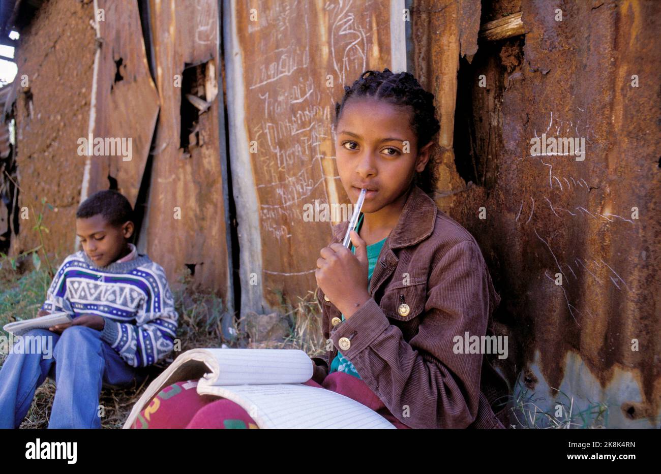 Ethiopia, Tigray; Girl and boy are making homework outside their home ...