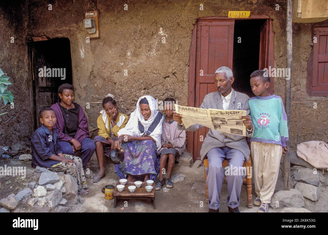 Ethiopia, Tigray; Family drinking tea in front of their adobe house ...