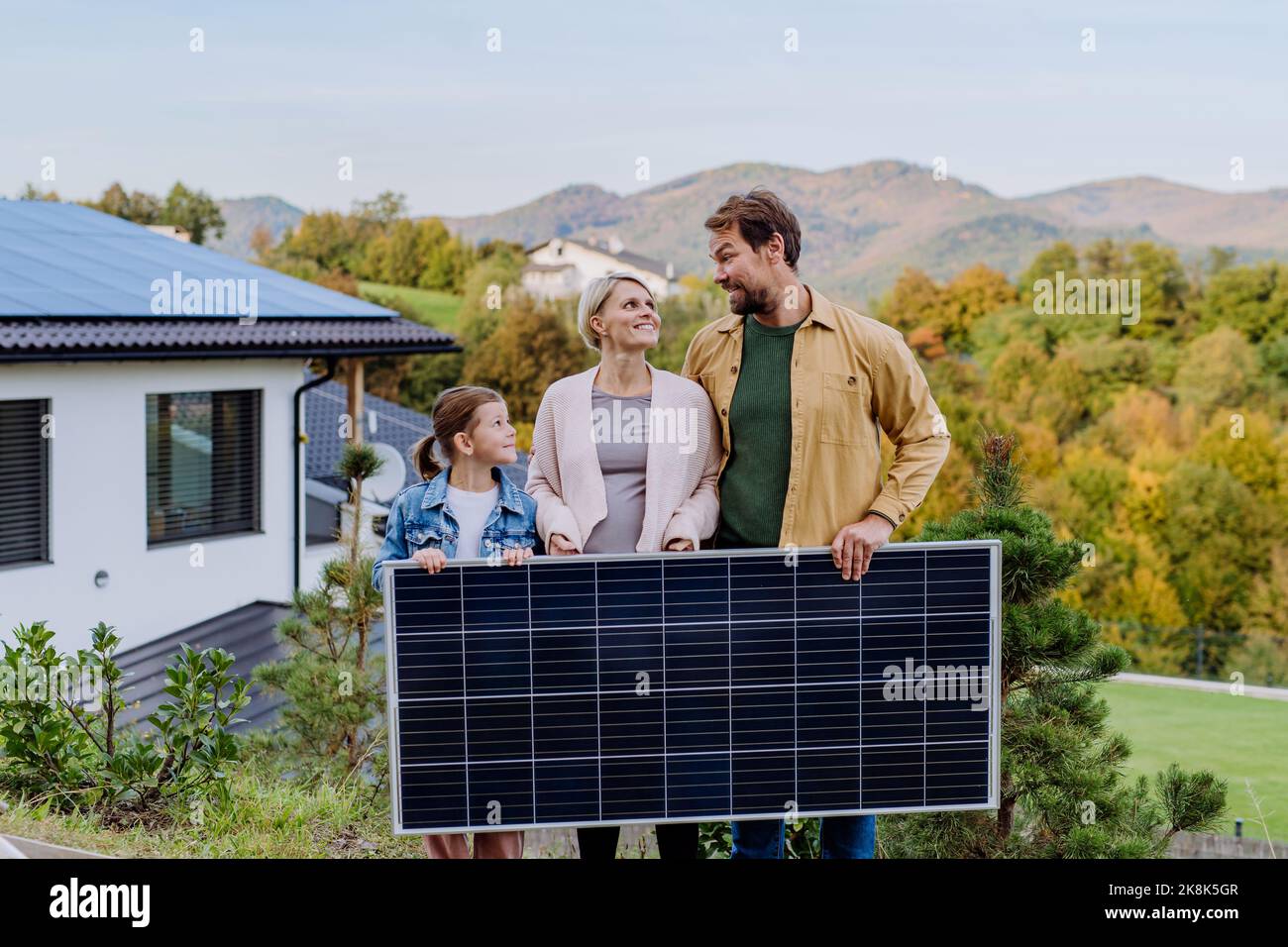 Happy family near their house with solar panel. Alternative energy ...