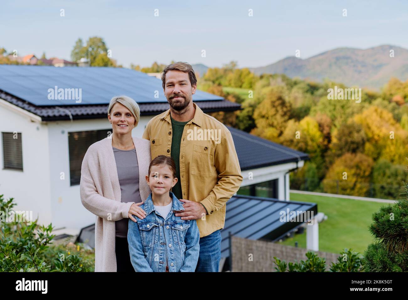 Happy family near their house with solar panels. Alternative energy ...