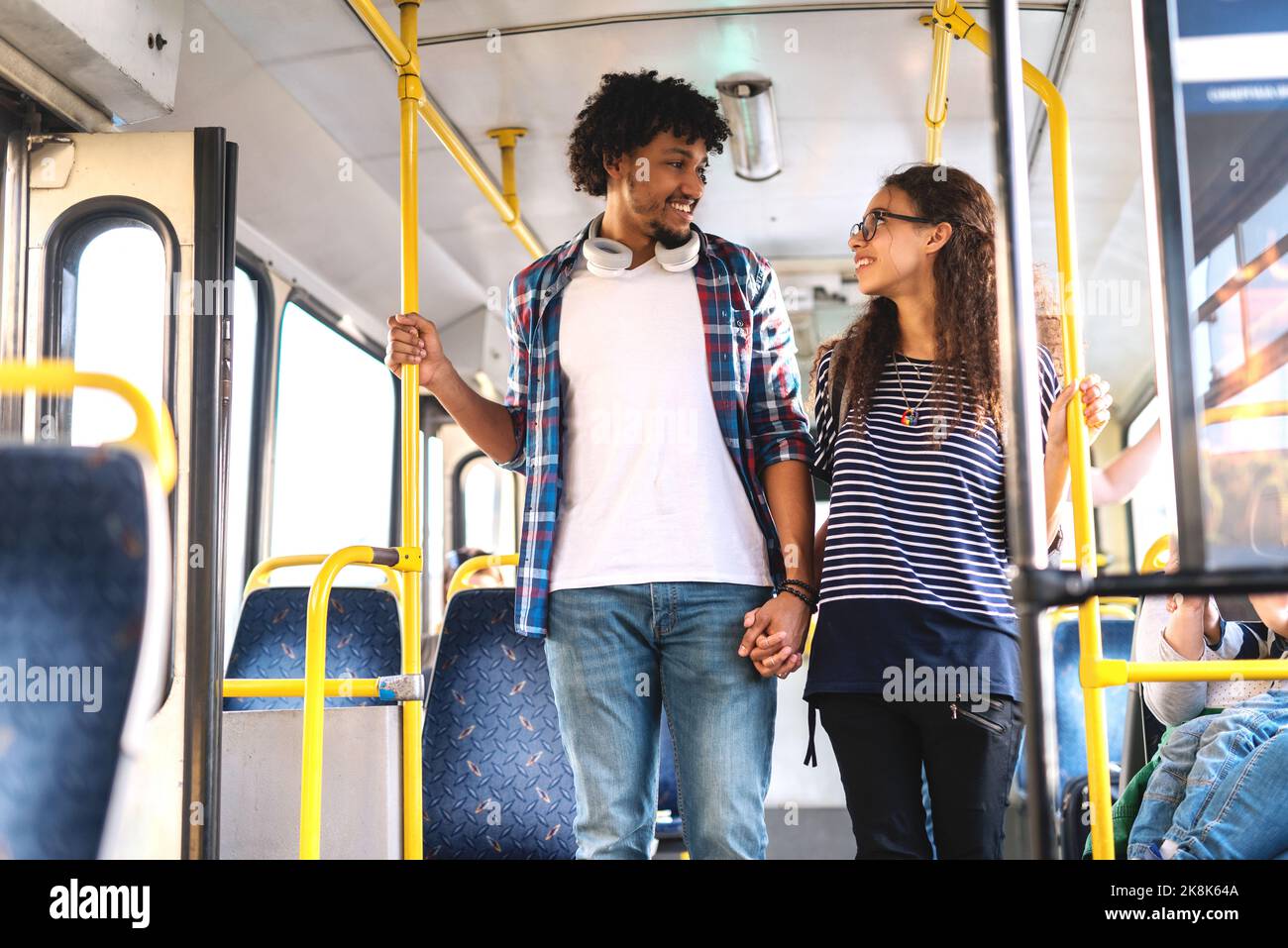 Happy multicultural couple standing and holding hands while riding in ...