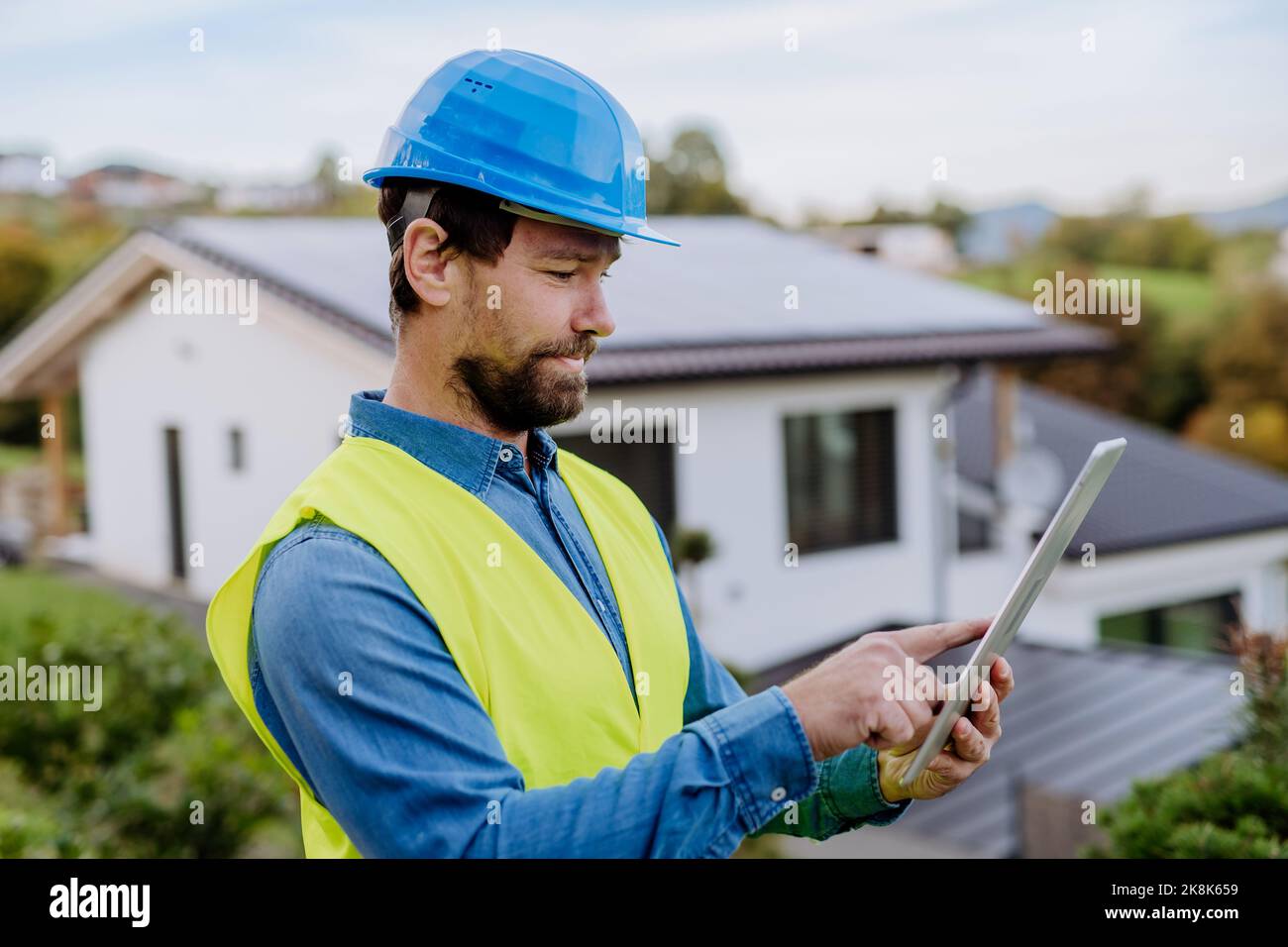 Smiling handyman solar installer standying in front of family house ...