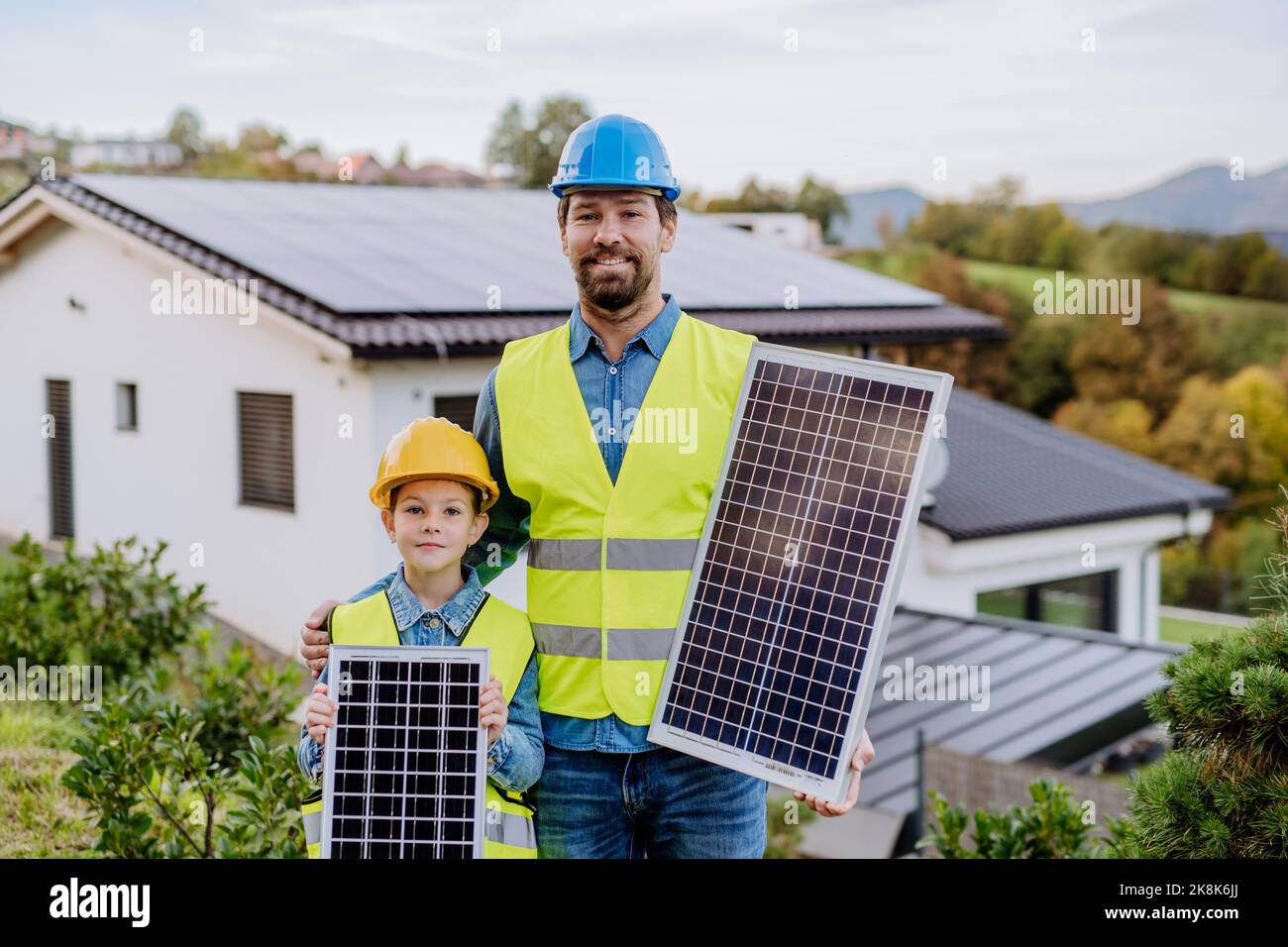Smiling handyman solar installer standying with his daughter and ...