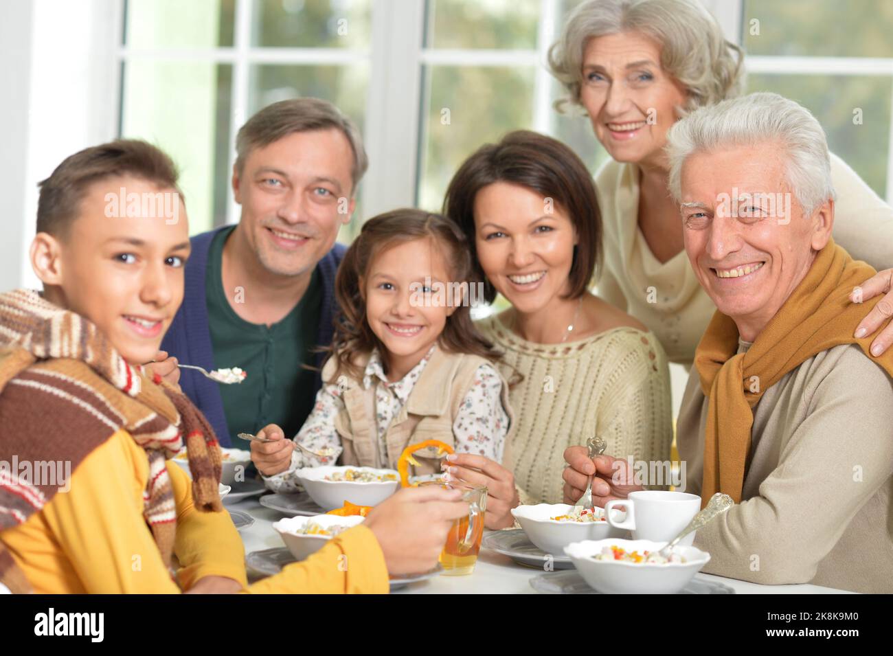 Happy family of different generations eating together Stock Photo - Alamy
