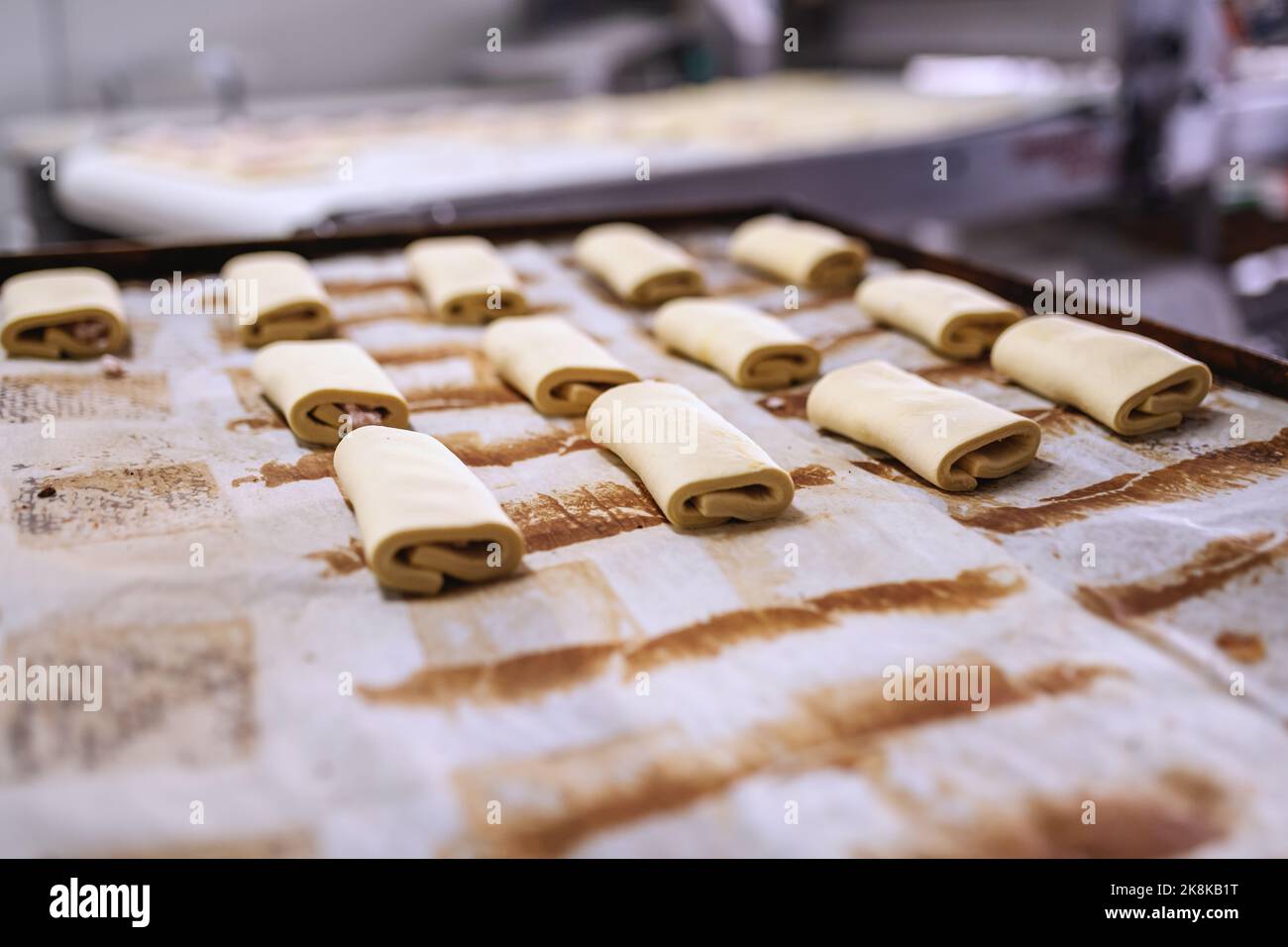 Close up of rolled sweet pastry on baking tray ready to be baked ...