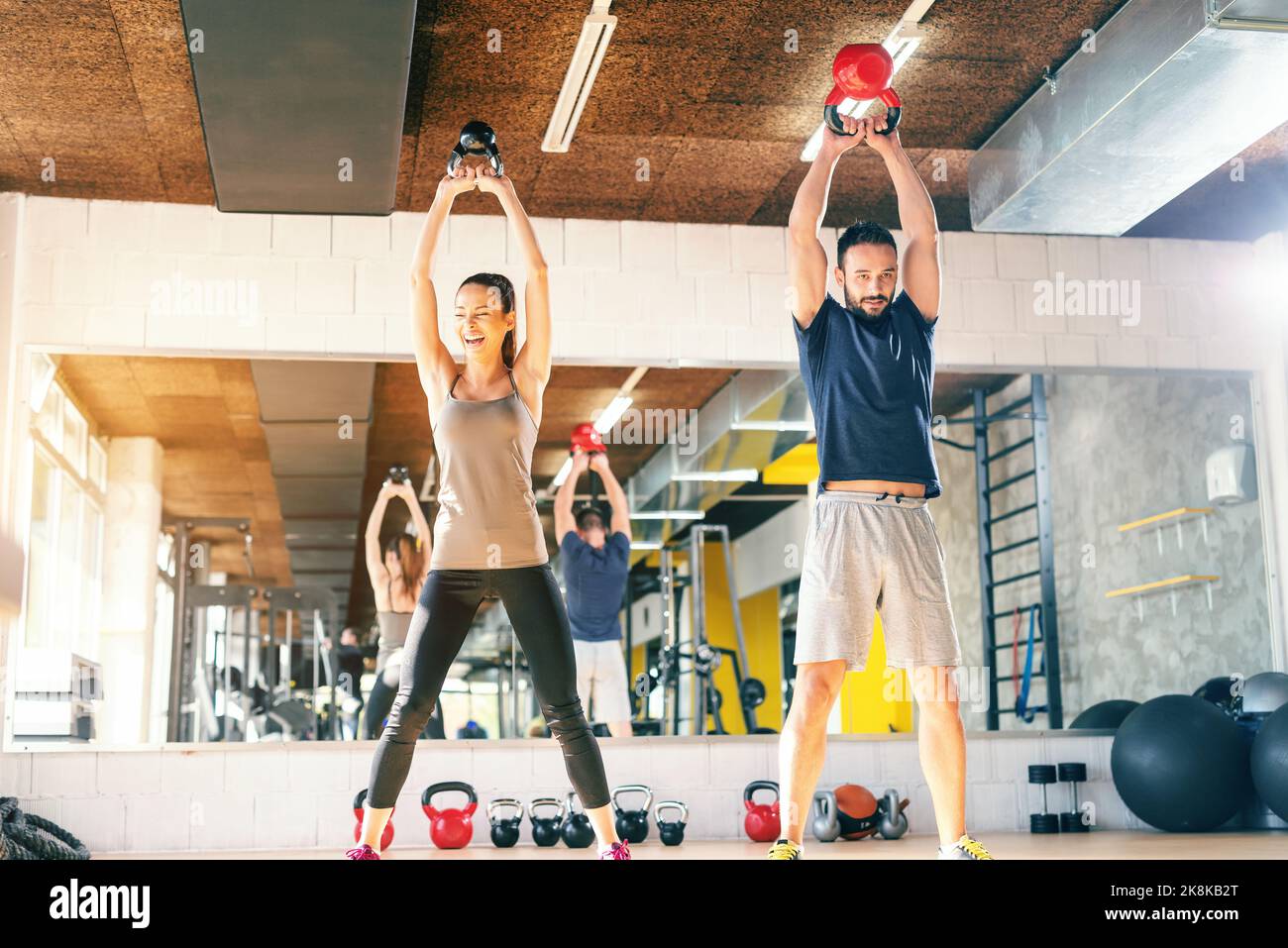 Happy Caucasian couple doing strength exercises with kettlebell while ...