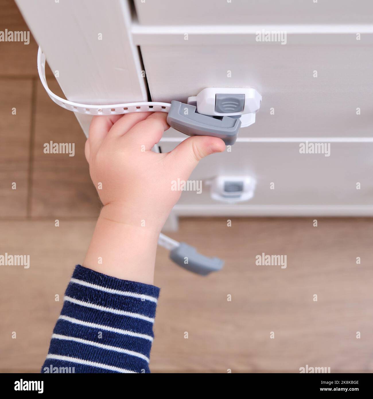 Baby opens the child lock on the closed drawer of the cabinet. Toddler ...